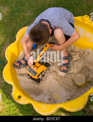 Kid playing in a sand pit. Kid on a ride in sand pit Stock Photo - Alamy