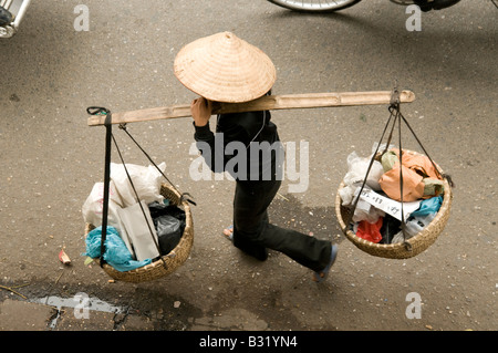 Woman with carrying pole and baskets on rice paddies trail, near Hanoi ...