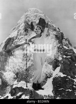 Young female climber atop a natural boulder outdoors, in Swiss Alps ...