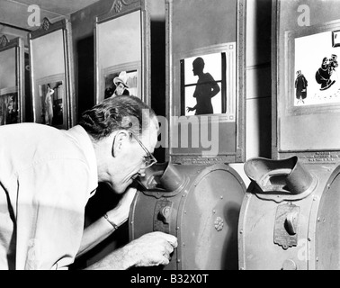 Man looking into a nickelodeon film machine Stock Photo - Alamy