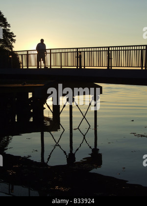 moody scene of person crossing bridge at sunset Stock Photo - Alamy