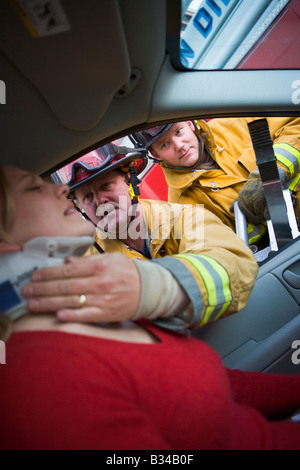 Fireman helping woman with neck brace while another fireman uses the ...