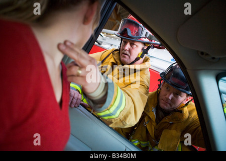 Fireman helping woman with neck brace while another fireman uses the ...