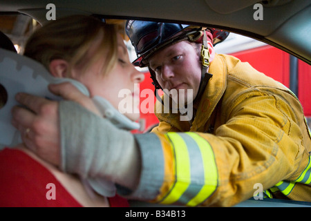 Fireman helping woman with neck brace while another fireman uses the ...