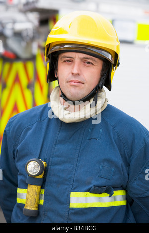 Fireman standing by fire engine wearing helmet Stock Photo - Alamy