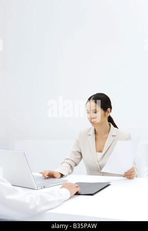cropped view of businesswoman using laptop near notebook, coffee cup ...