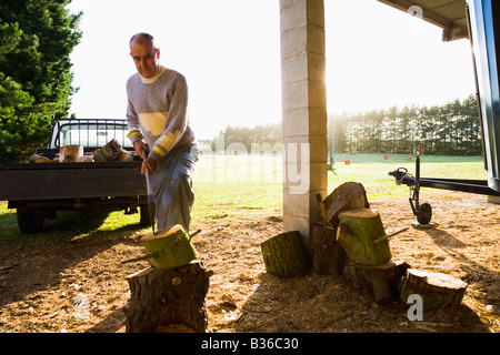 Man chopping wood with an ax in his hand. Standing by a log for ...