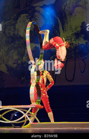 Acrobat in mid air jumps through hoop and over four others at ...