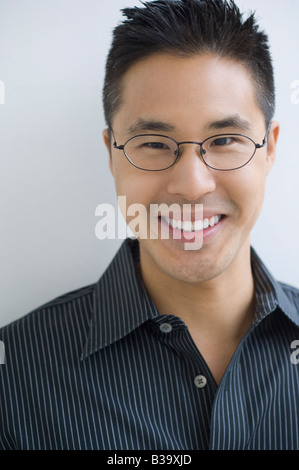 Young asian man in eyeglasses and black T-shirt leaning on table ...