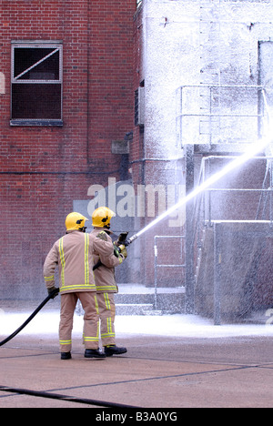 UK firefighters spraying fire-fighting foam onto a burning building ...