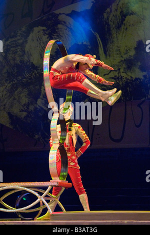 Acrobat in mid air jumps through hoop and sumersaults at acrobatics ...
