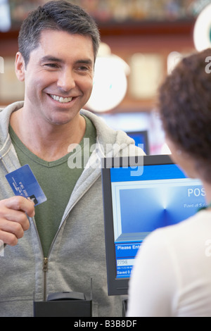Hispanic man holding credit card at retail shop pointing finger to one ...