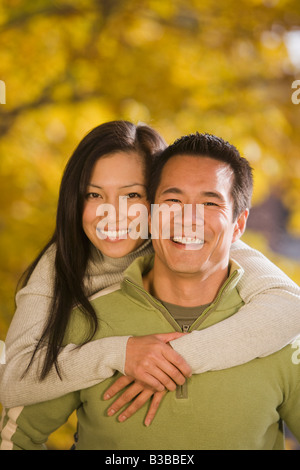 Man looking at camera while hugging asian girlfriend on terrace of cafe ...
