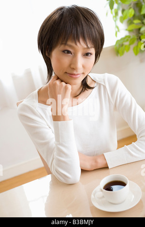 Young Asian woman sitting on couch waving at laptop during video call ...