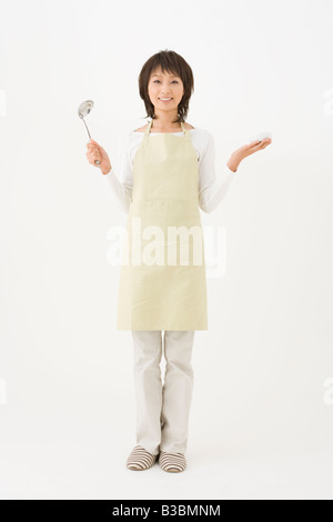 Smiling young housewife cooking with ladle at her kitchen at home Stock ...