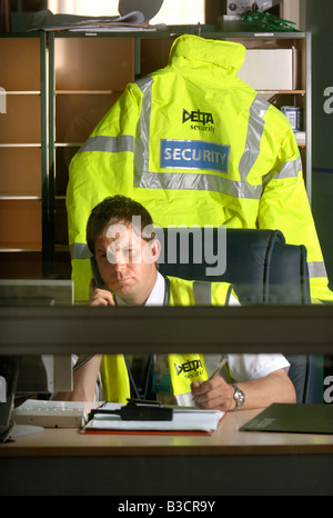 A SECURITY GUARD LOGS INFORMATION AT AN OFFICE DESK UK Stock Photo - Alamy