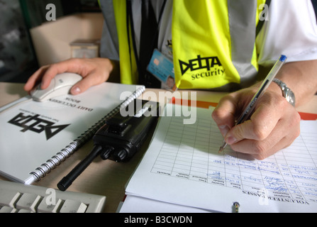A SECURITY GUARD LOGS INFORMATION AT AN OFFICE DESK UK Stock Photo - Alamy