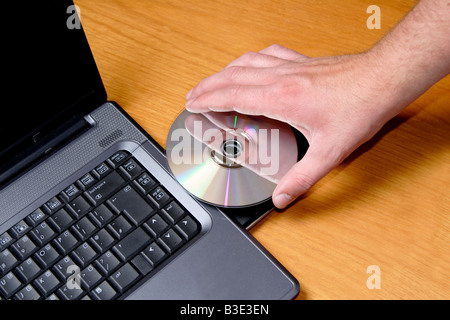 Inserting a CD into a CD rom drive on a laptop computer Stock Photo - Alamy