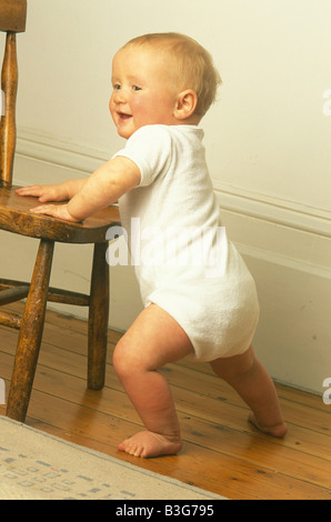 baby learning to stand pulling himself up with a small chair Stock ...