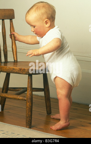 baby learning to stand pulling himself up with a small chair Stock ...