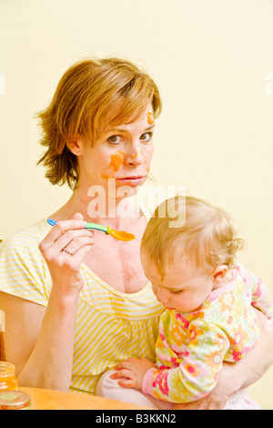 Frustrated mother trying to feed messy baby Stock Photo - Alamy