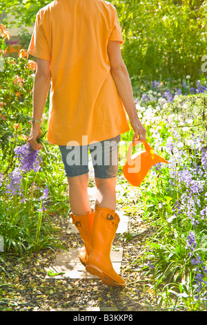 Woman walking through flowered path in garden Stock Photo - Alamy