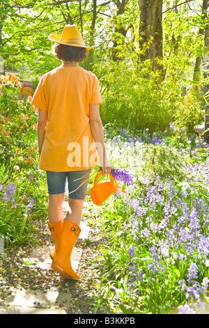 Woman walking through flowered path in garden Stock Photo - Alamy