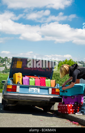 Woman loading car trunk with colorful suitcases Stock Photo - Alamy