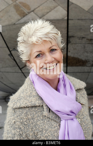 Portrait of happy attractive older woman sitting outside in city Stock ...
