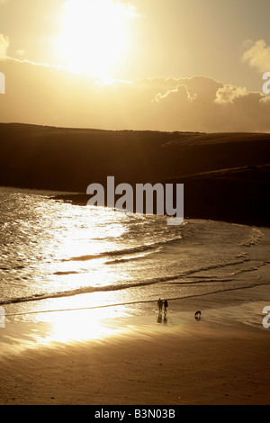 Couple walking a dog on Manorbier beach Wales at sunset Stock Photo - Alamy