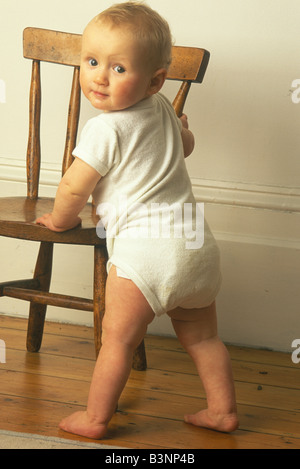 baby learning to stand pulling himself up with a small chair Stock ...