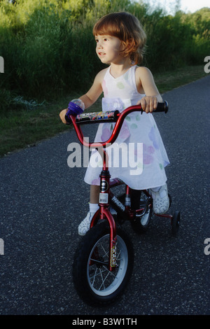 Girl and toddler riding a bicycle in a field Stock Photo - Alamy