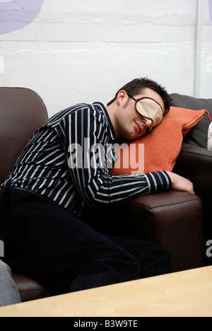 Young man in sleeping mask turning off alarm clock while lying on bed ...