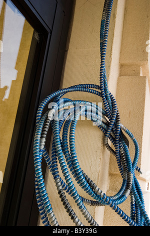 Coiled electrical cable hanging outside a building Stock Photo - Alamy