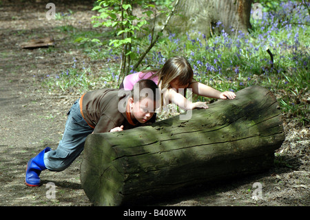 A boy and girl trying to roll a log Stock Photo - Alamy