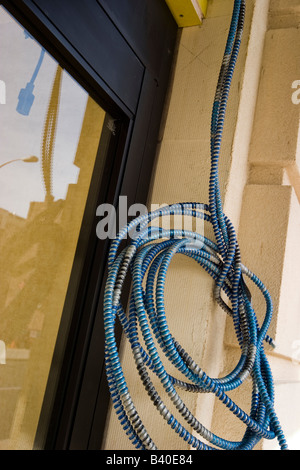 Coiled electrical cable hanging outside a building Stock Photo - Alamy