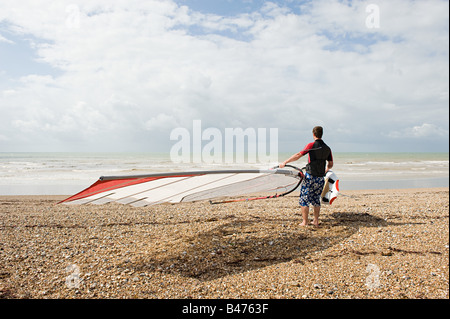 A Windsurfer carrying his board to the beach Stock Photo - Alamy