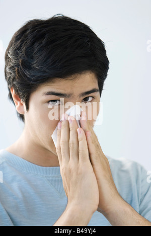 Asian man blowing nose on sofa at home for cold and flu relief Stock ...