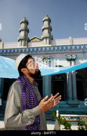 Asian Muslim man in praying position (salat) on prayer rug with the ...