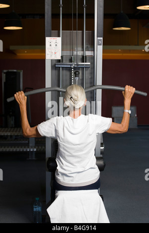 Weight training. Woman using pull-down weights in a gymnasium Stock ...