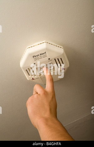 Finger presses test button on home smoke detector Stock Photo - Alamy