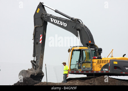 Waste Management Landfill workers with a backhoe placing dirt on trash ...