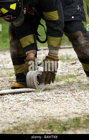 A firefighter rolling the hose after it being used at a scene Stock ...