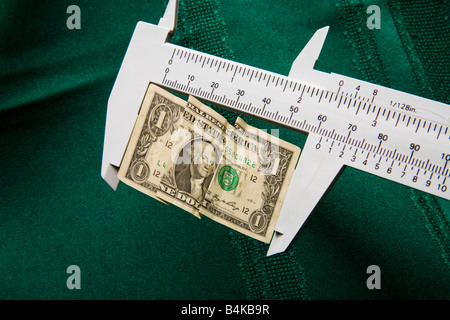US dollar being measured in calipers. value reduce lose lost mortgage ...