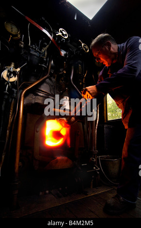 A fireman on the footplate shoveling coal on the steam locomotive of ...