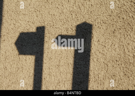 two footpath signs shadow on house wall in sun Stock Photo - Alamy