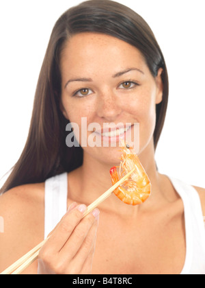 Young brunette woman eating prawn sushi using chopsticks looking ...