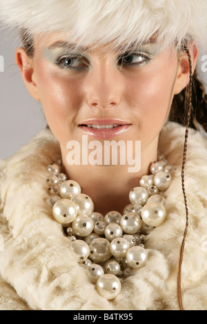 Woman wearing fake fur coat and enjoying walk outdoors in winter park ...
