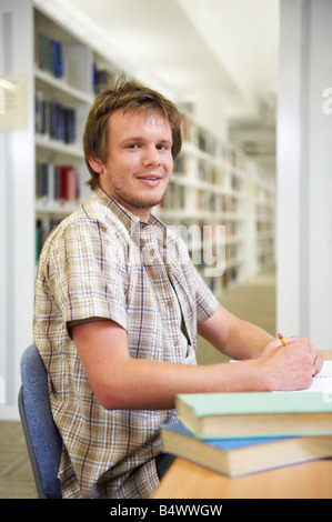 Smiling guy posing in library, holding books and notes Stock Photo - Alamy