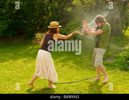 Woman spraying man with garden hose Stock Photo - Alamy
